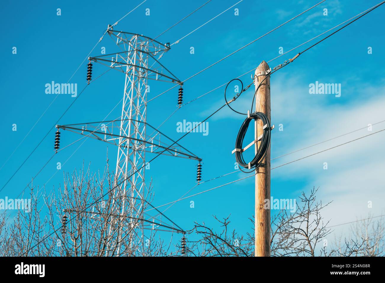 Old wooden electricity pole and overhead powerline tower, selective ...