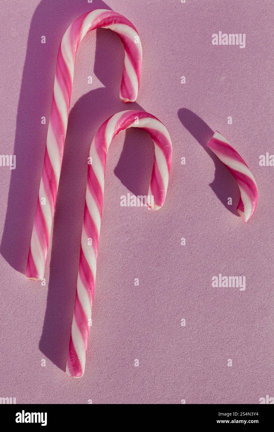 Two pink and white striped candy canes arranged artistically on a ...