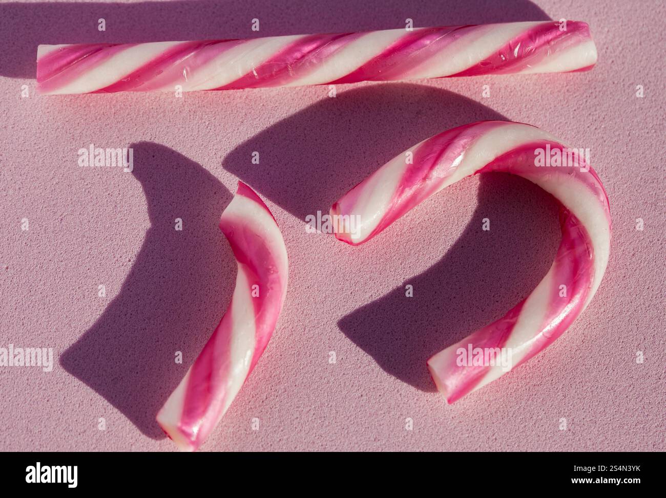 A broken pink and white candy cane placed in a creative arrangement on ...
