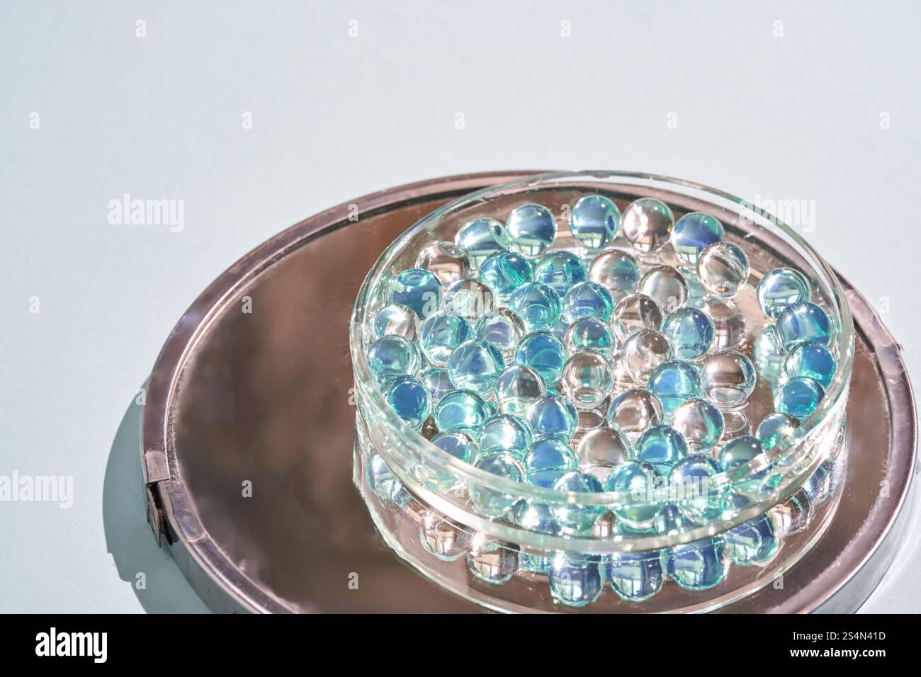 Glass marbles in transparent dish on metal tray with light blue ...