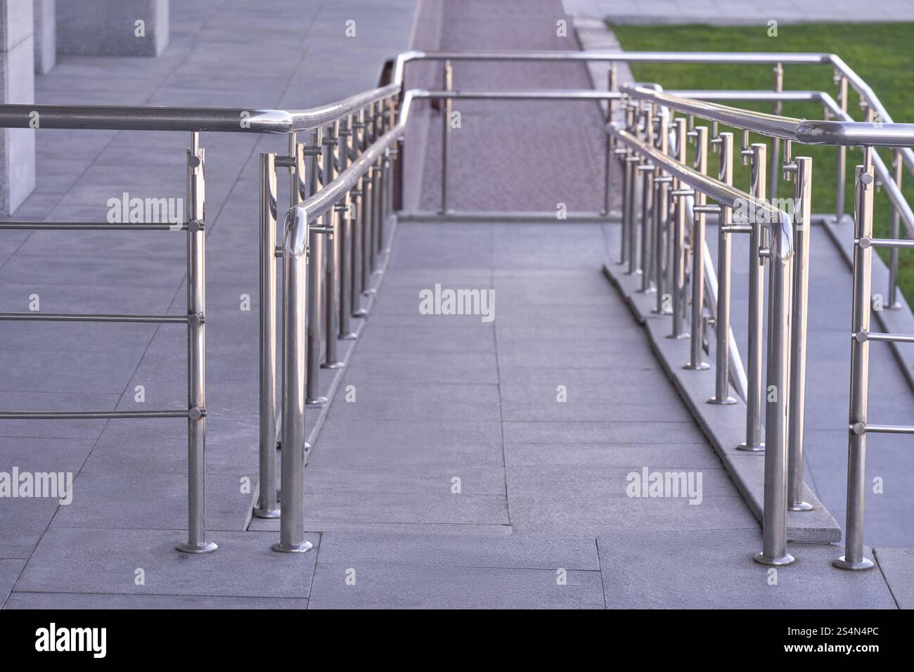 Modern accessibility ramp with stainless steel railings on sidewalk ...