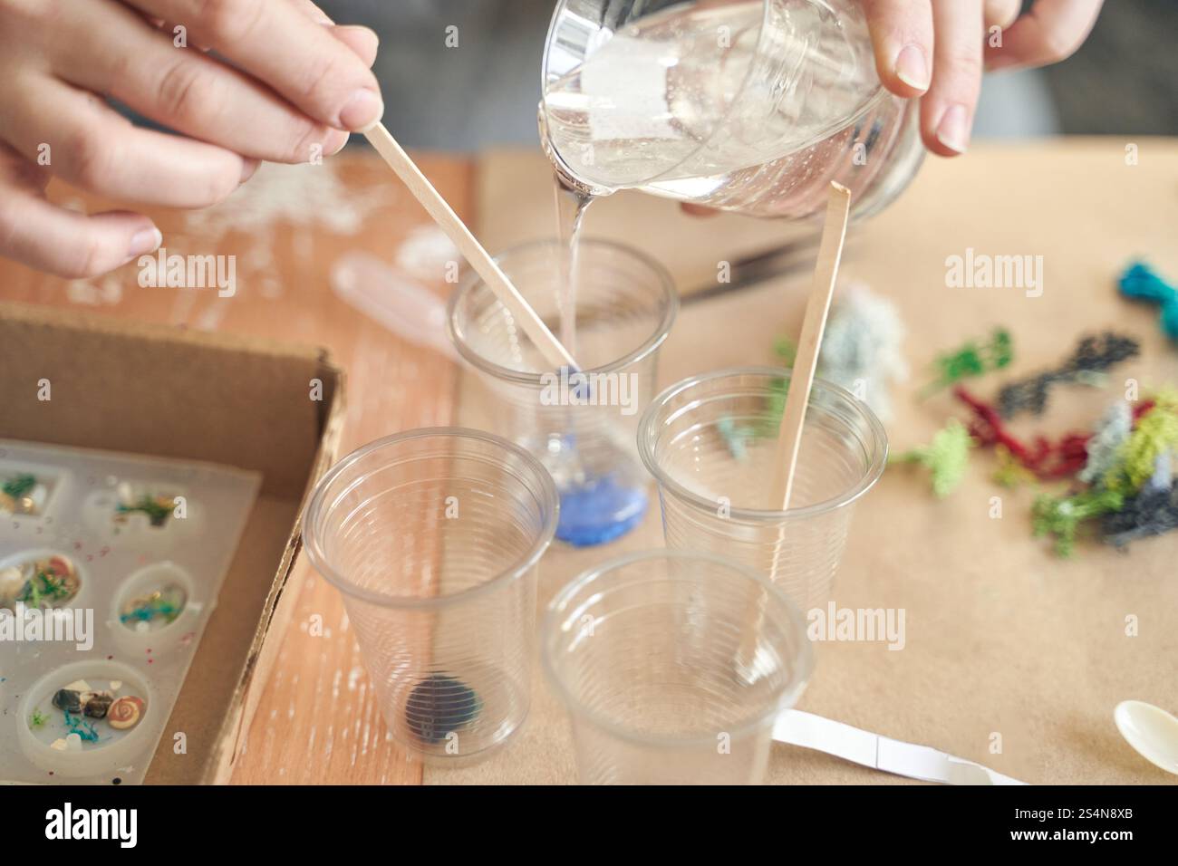 Crafting with resin: hands pouring liquid into molds for diy jewelry ...