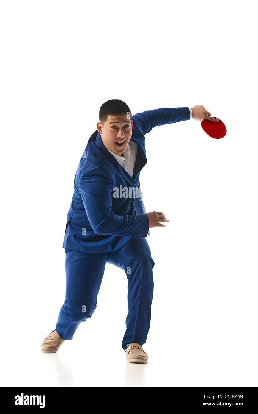 Man in blue suit energetically swinging red ping-pong paddle while ...