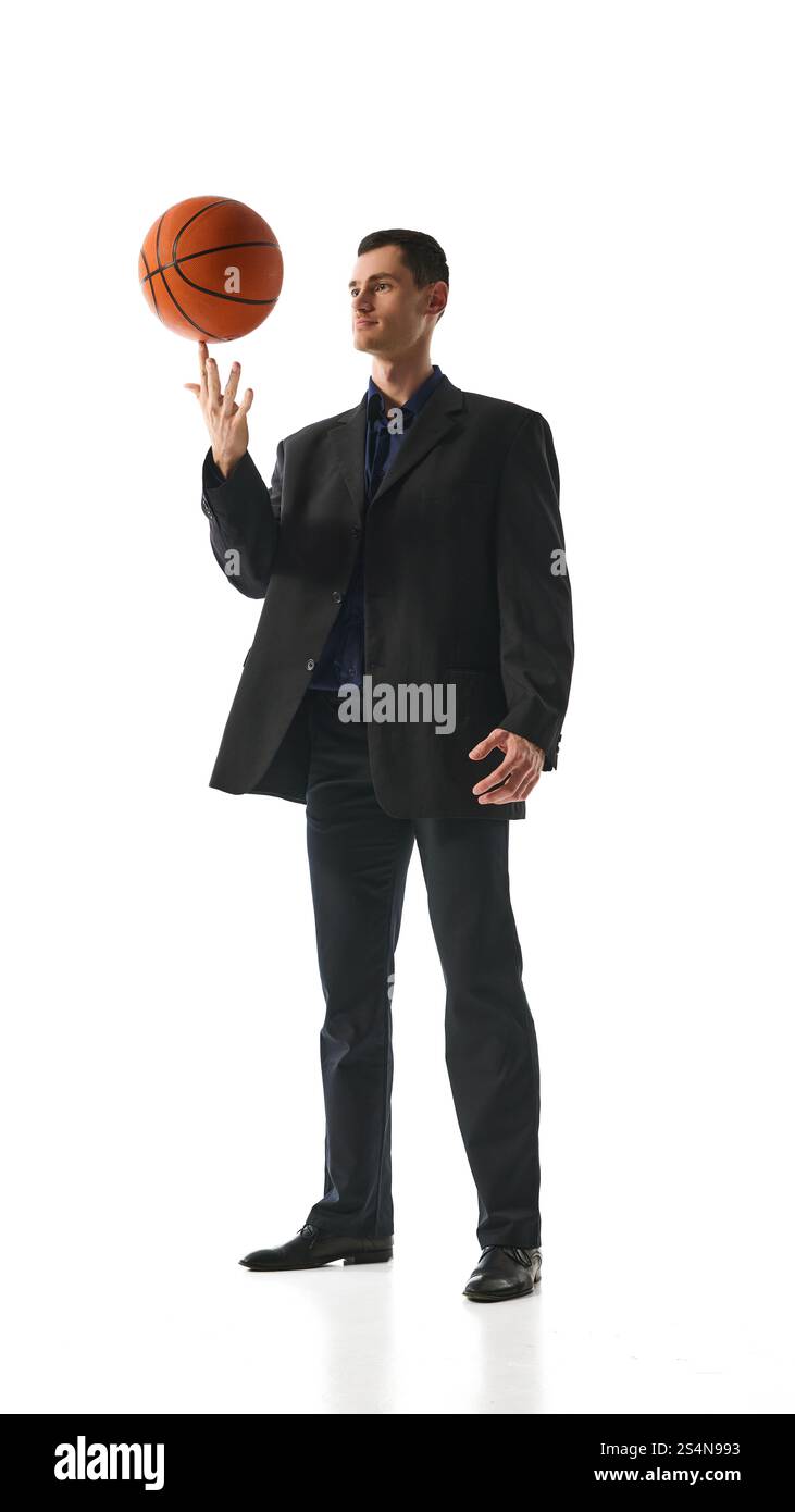 Man in black suit spinning basketball on fingertip with focused ...