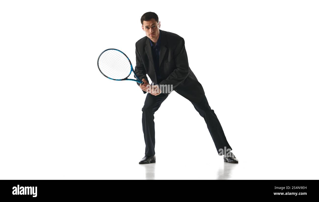 Man in black suit holding tennis racket in defensive stance, reflecting ...