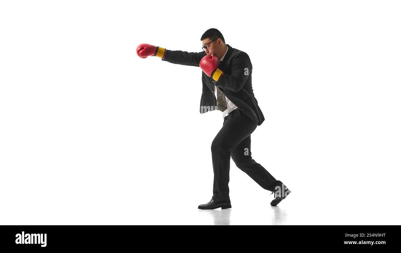 Man in suit and tie strikes forward boxing pose, red gloves raised as ...