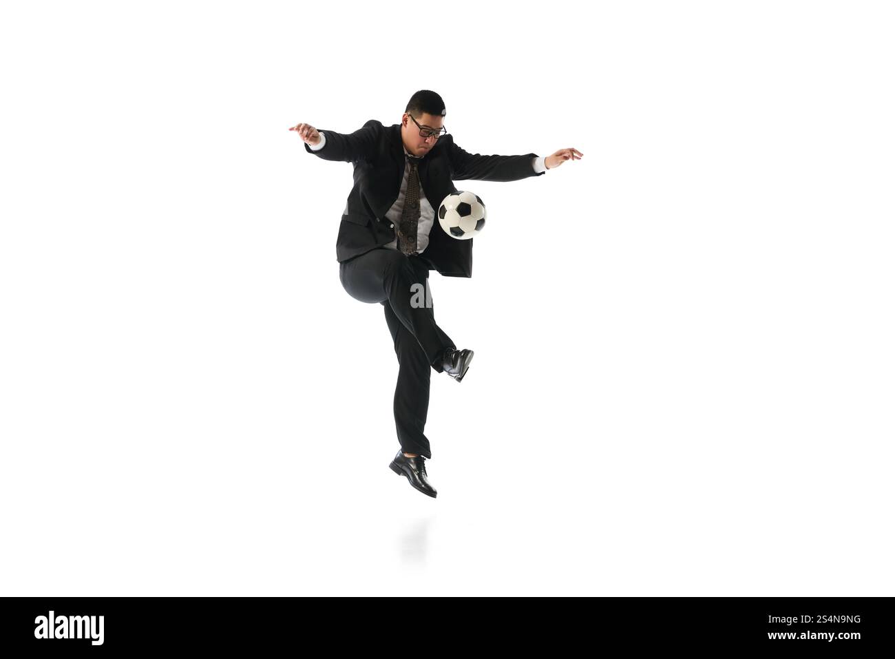 Man performs high soccer kick in suit, blending professionalism with ...