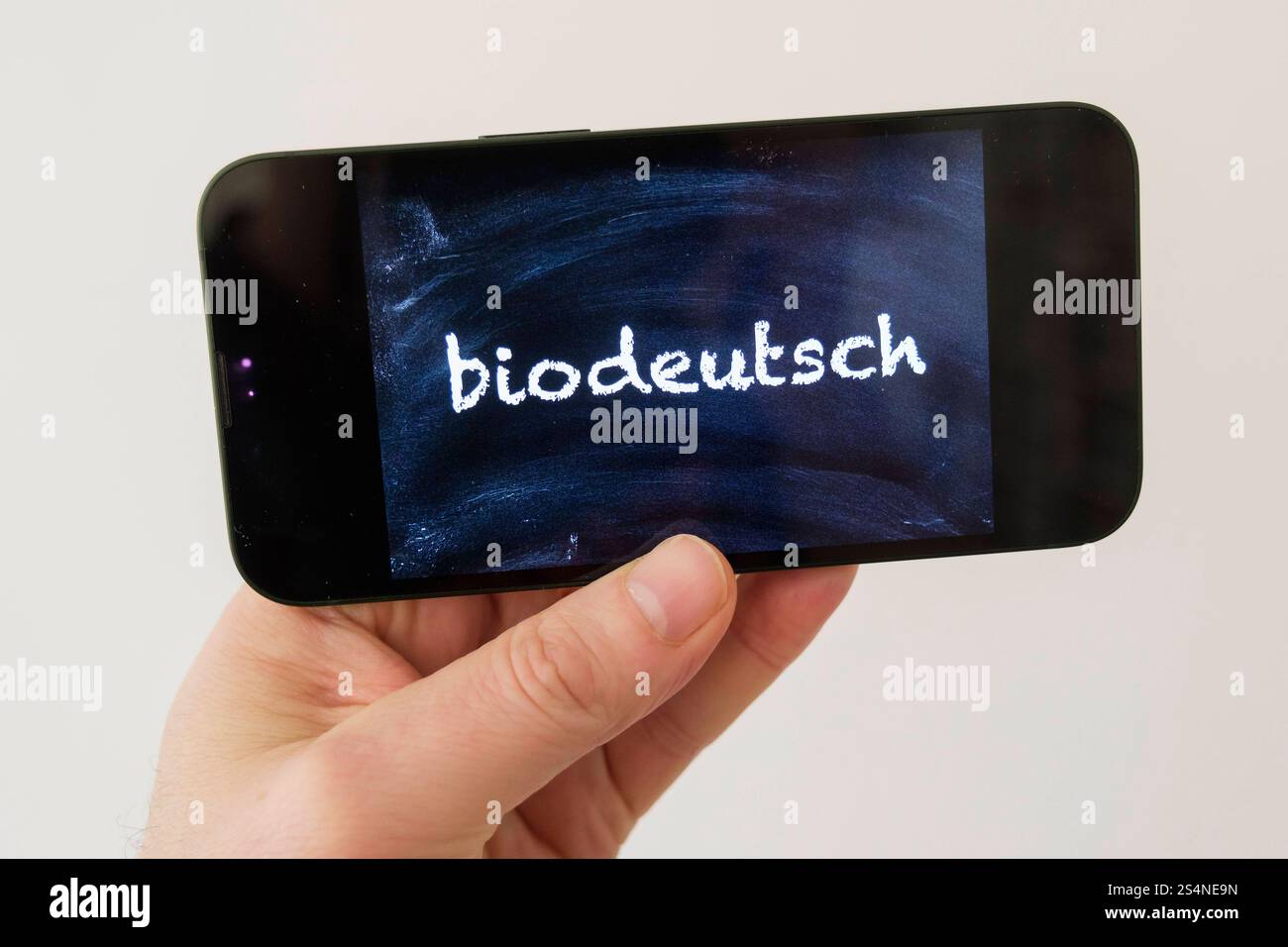 Hand mit Mobiltelefon mit dem Unwort des Jahres 2024 biodeutsch ...