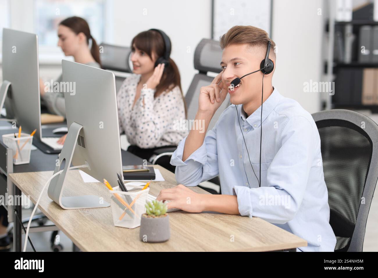 Salesman talking to client via headset at desk in office Stock Photo ...