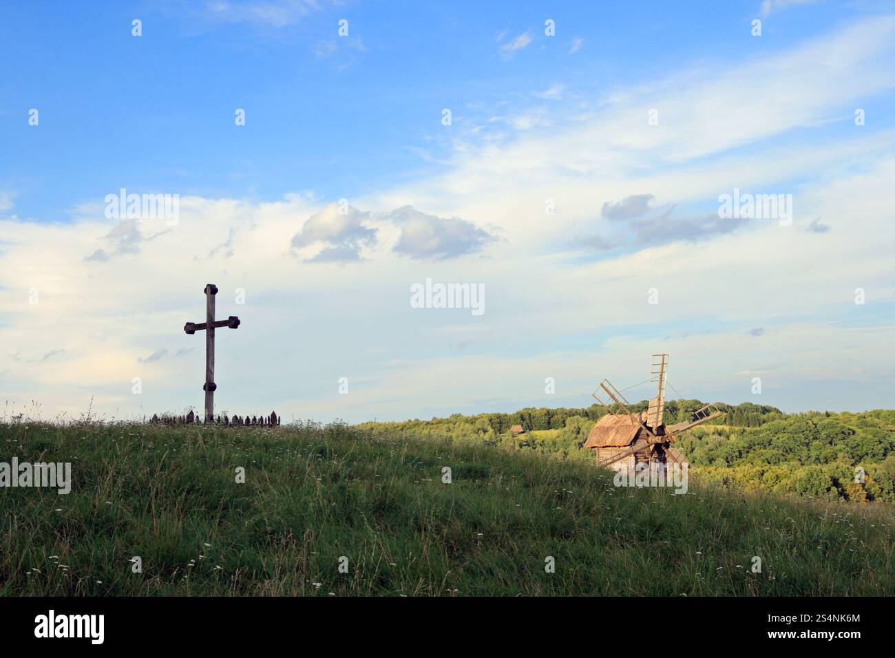 Christian wood cross on grass overgrown hill (forest colony and ...