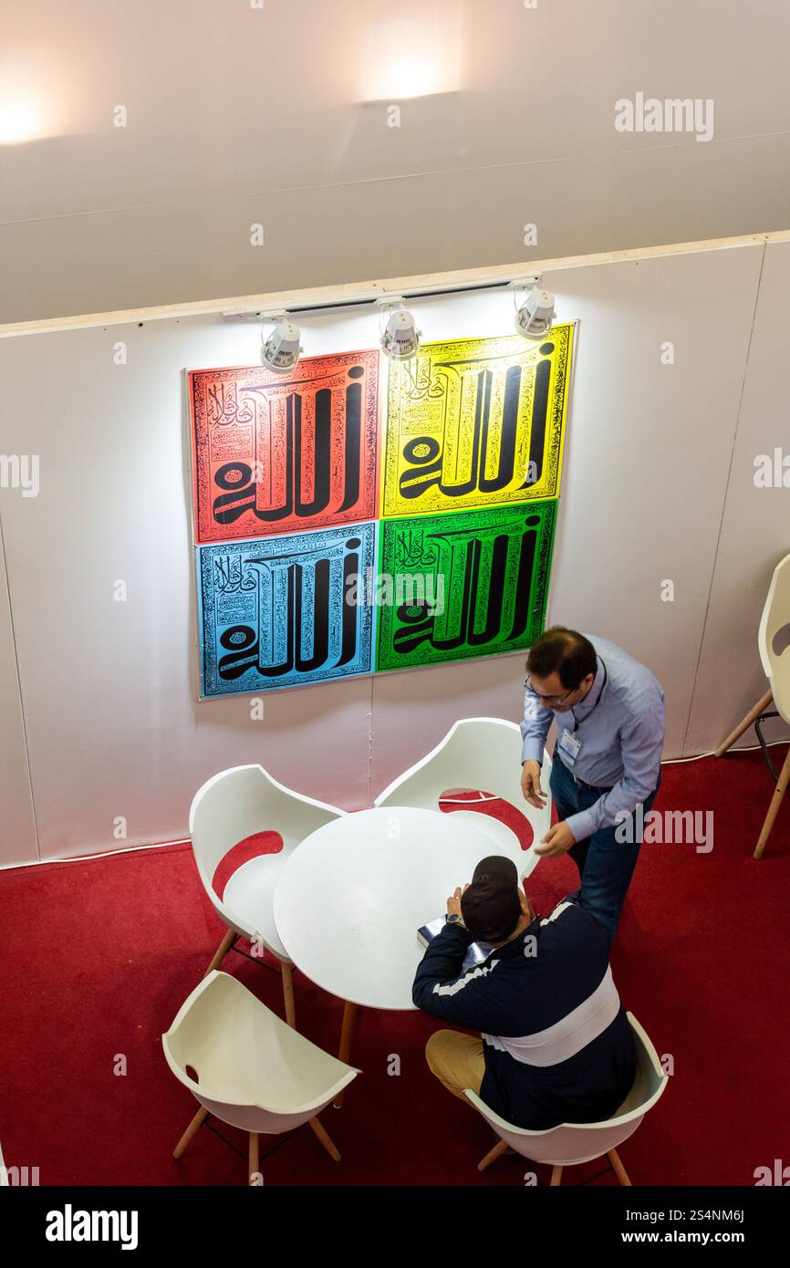 Two artists at a round table in front of colorful Islamic wall art in ...