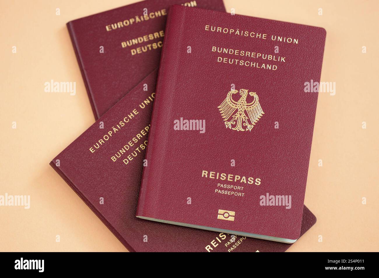 Three German passports on orange background, close-up shot. Symbol of ...