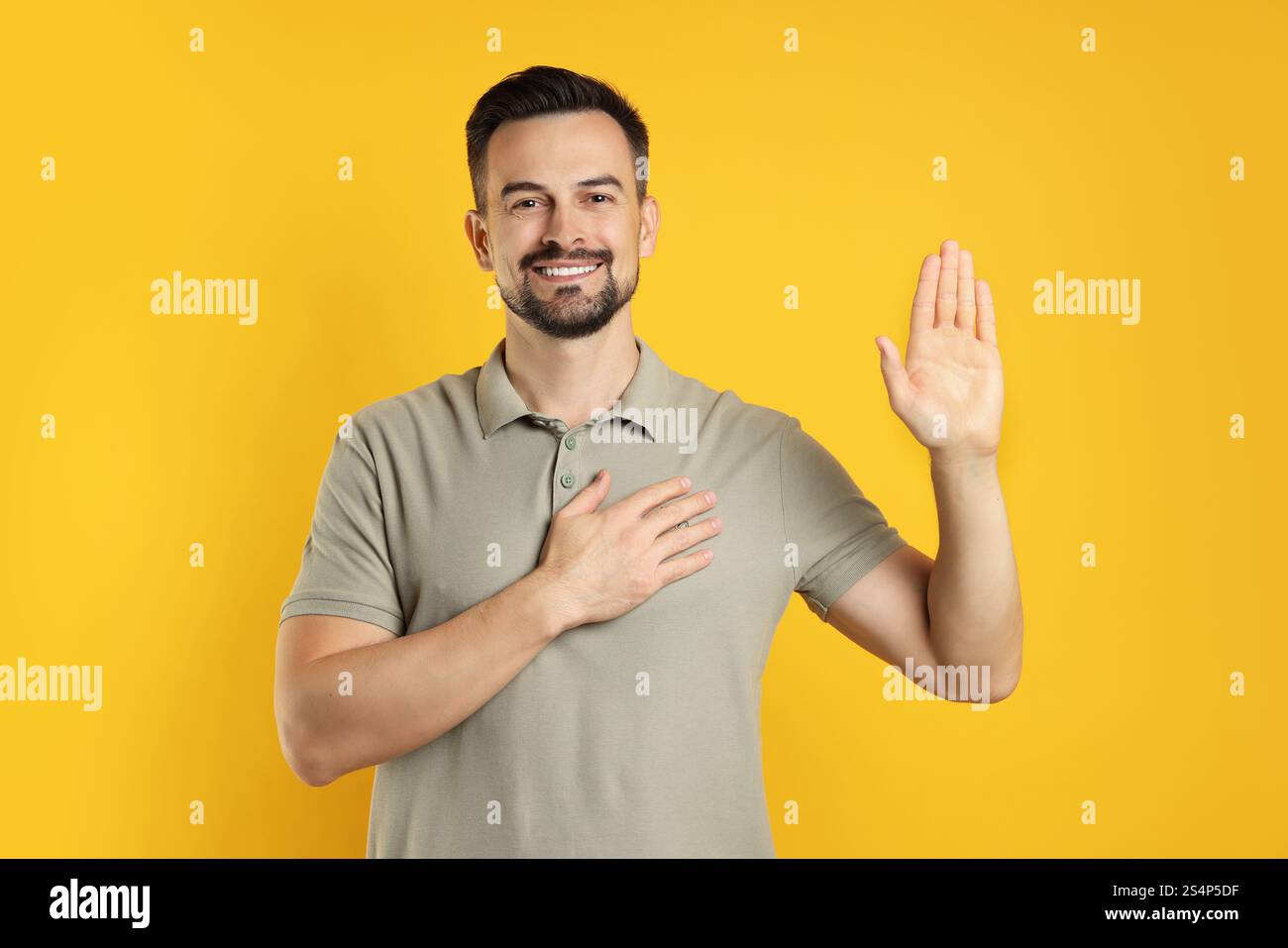 Man making promise with raised hand on orange background. Oath gesture ...
