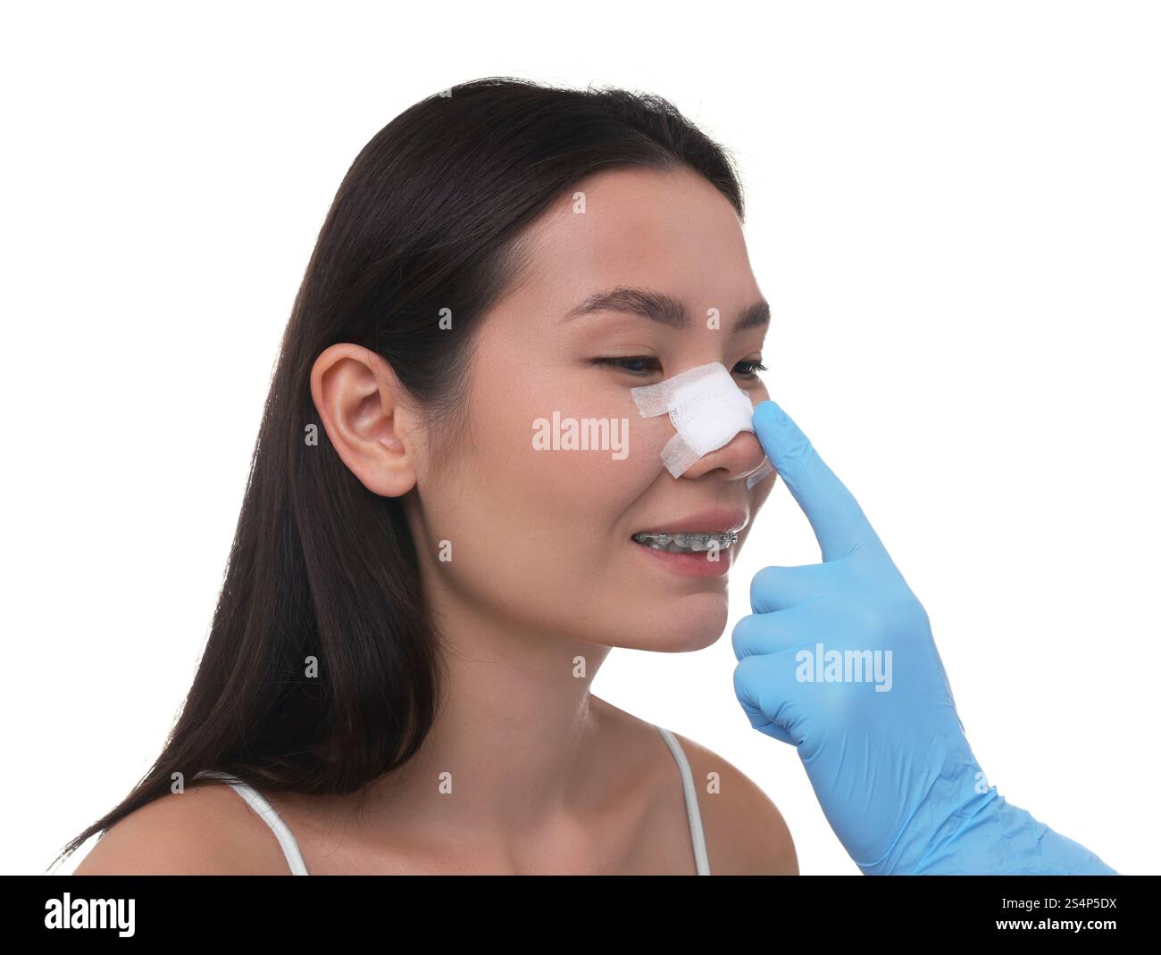 Doctor checking patient's nose after plastic surgery operation on white ...
