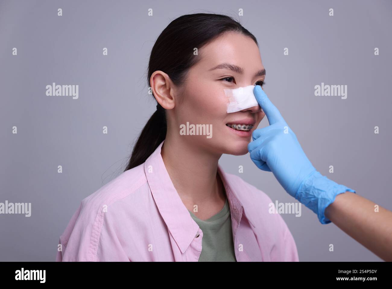 Doctor checking patient's nose after plastic surgery operation on light ...