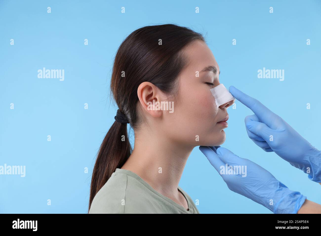 Doctor checking patient's nose after plastic surgery operation on light ...