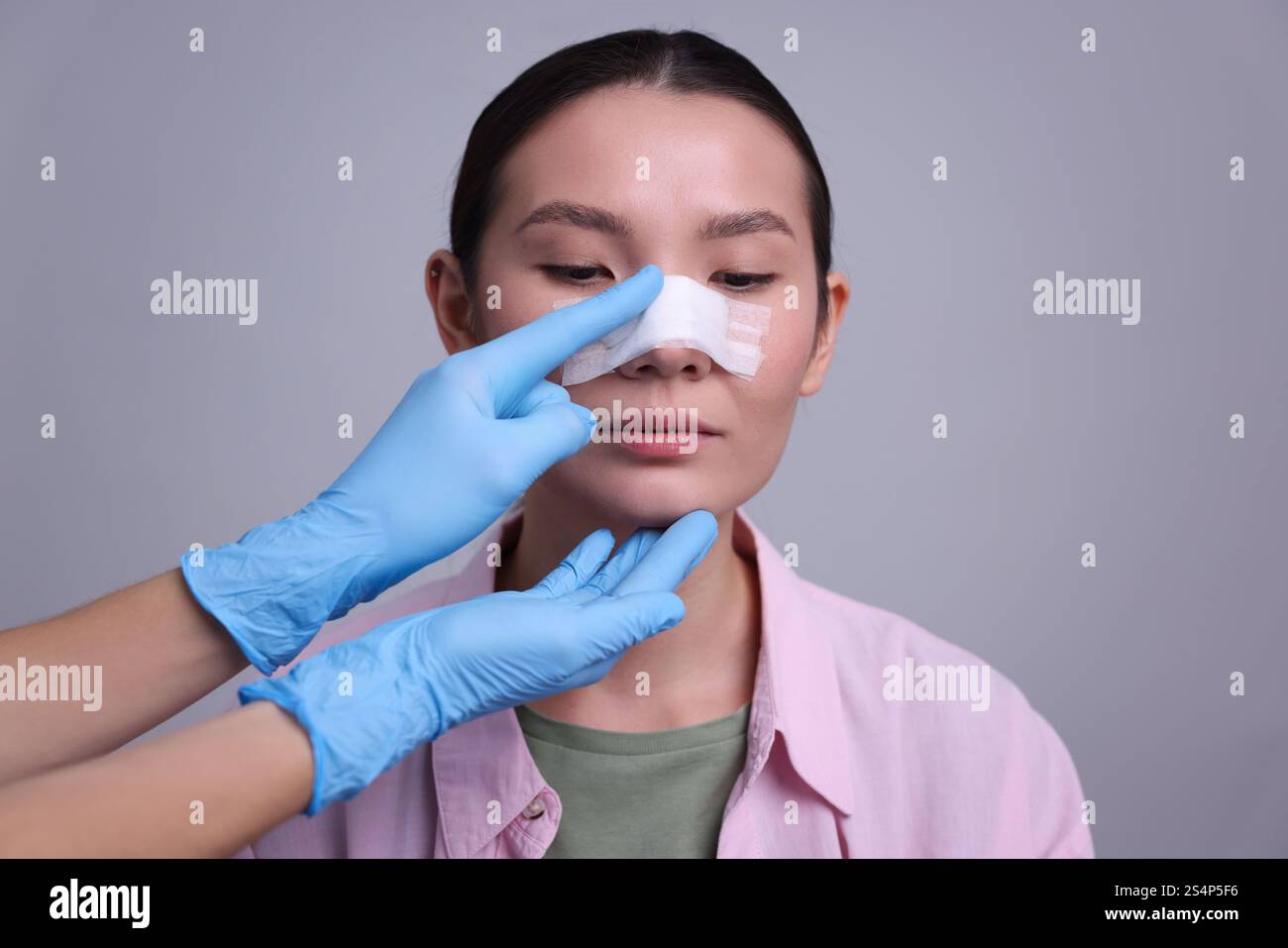 Doctor checking patient's nose after plastic surgery operation on light ...