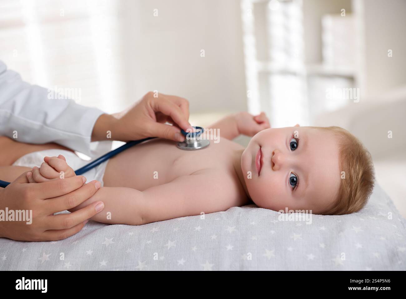Pediatrician examining little child with stethoscope in clinic, closeup ...