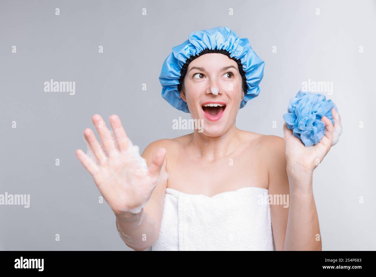 Emotional woman with shower cap and mesh sponge making stop gesture on ...