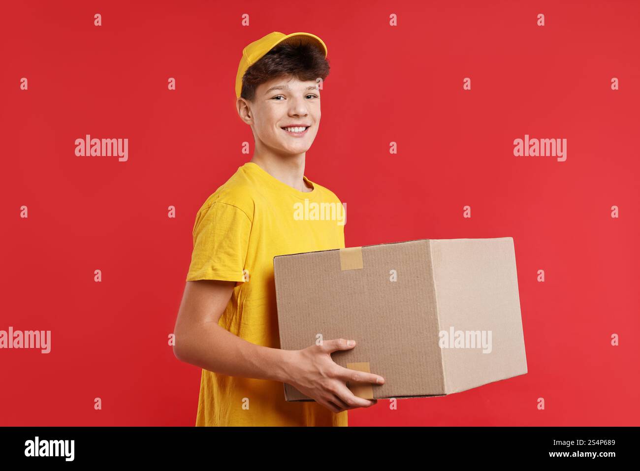 Teenage boy with parcel working as courier on red background Stock ...