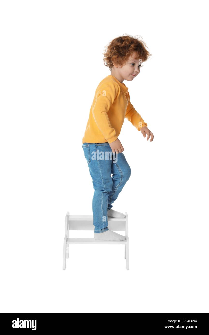Little boy standing on step stool against white background Stock Photo ...