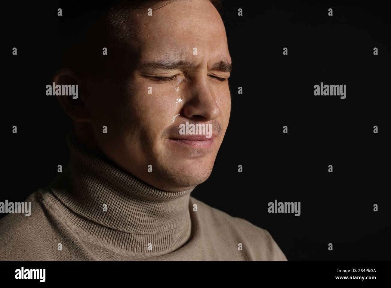 Distressed young man crying on black background Stock Photo - Alamy