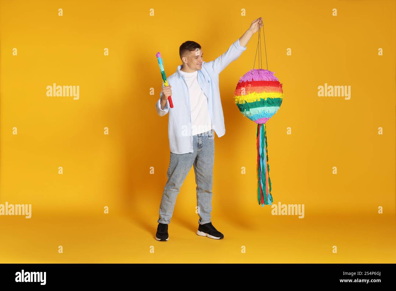 Happy man breaking pinata on yellow background Stock Photo - Alamy