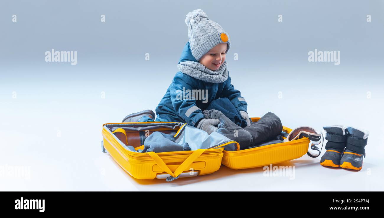 Cute little kid, pre-school boy, packing vibrant yellow suitcase with ...