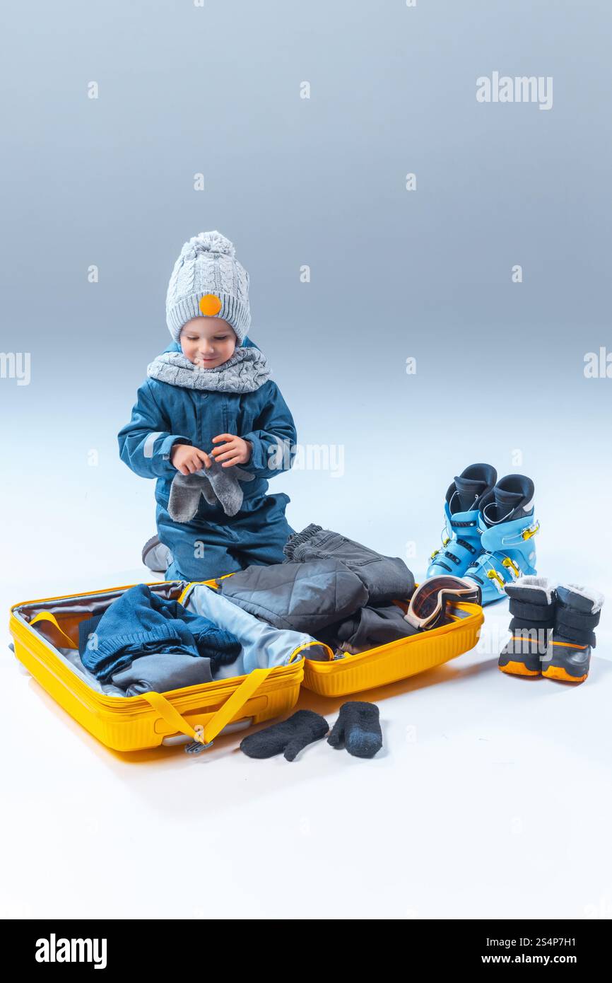 Cute little kid, pre-school boy, packing vibrant yellow suitcase with ...