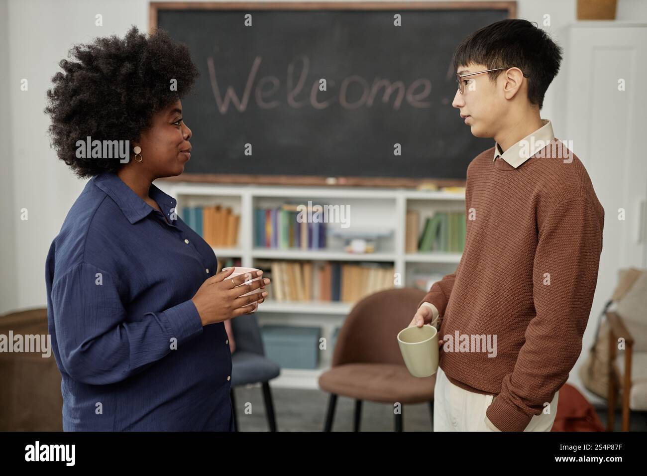 Side view portrait of Asian teenage boy talking to female teacher or ...