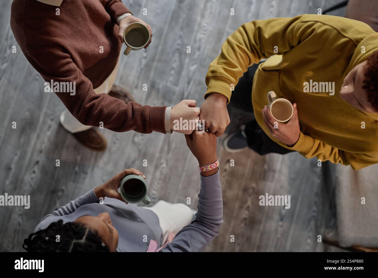 Top down view at three teenagers doing fist bump standing in circle ...