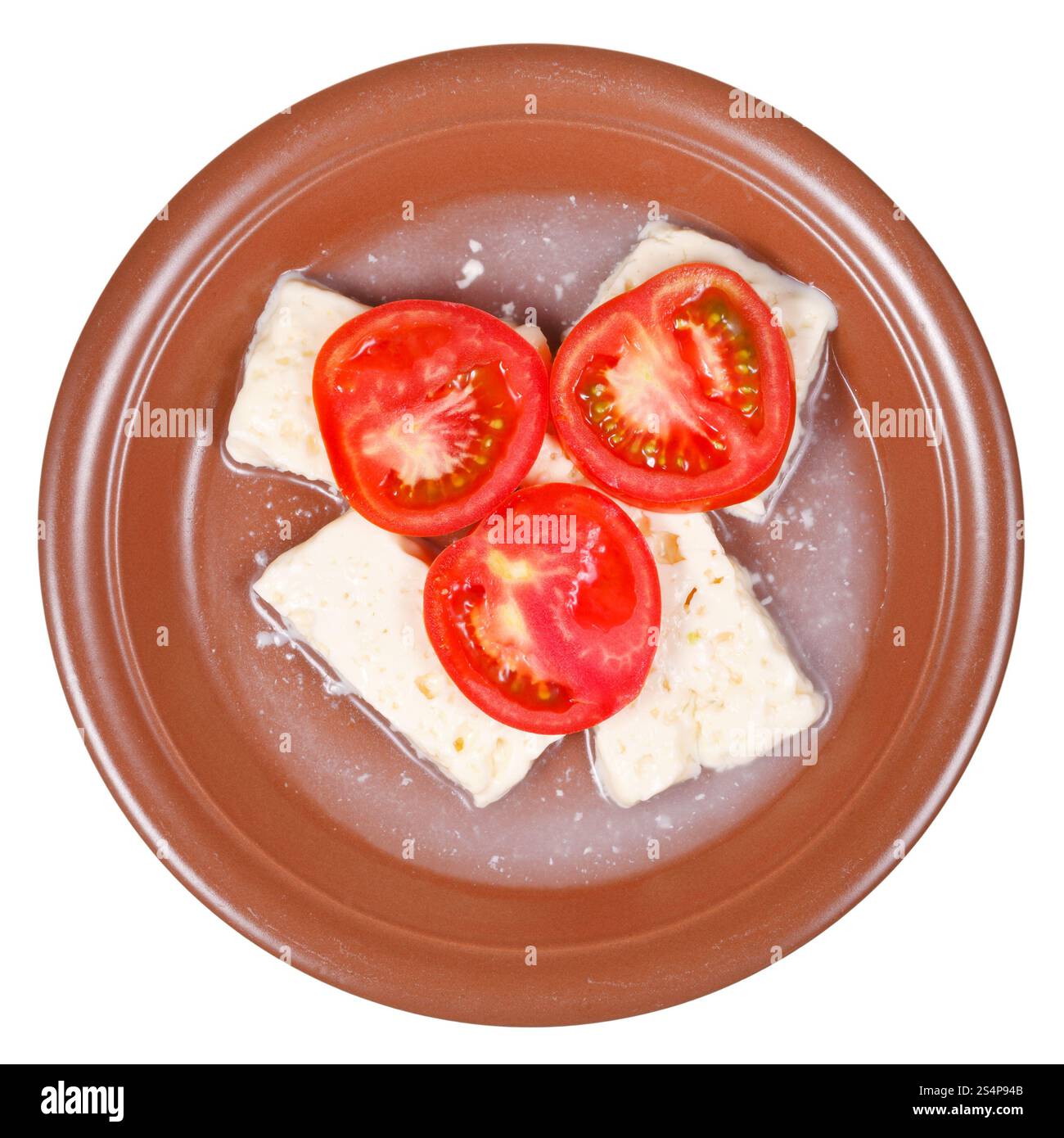 top view of sliced tomatoes and brined cheese on ceramic plate isolated ...