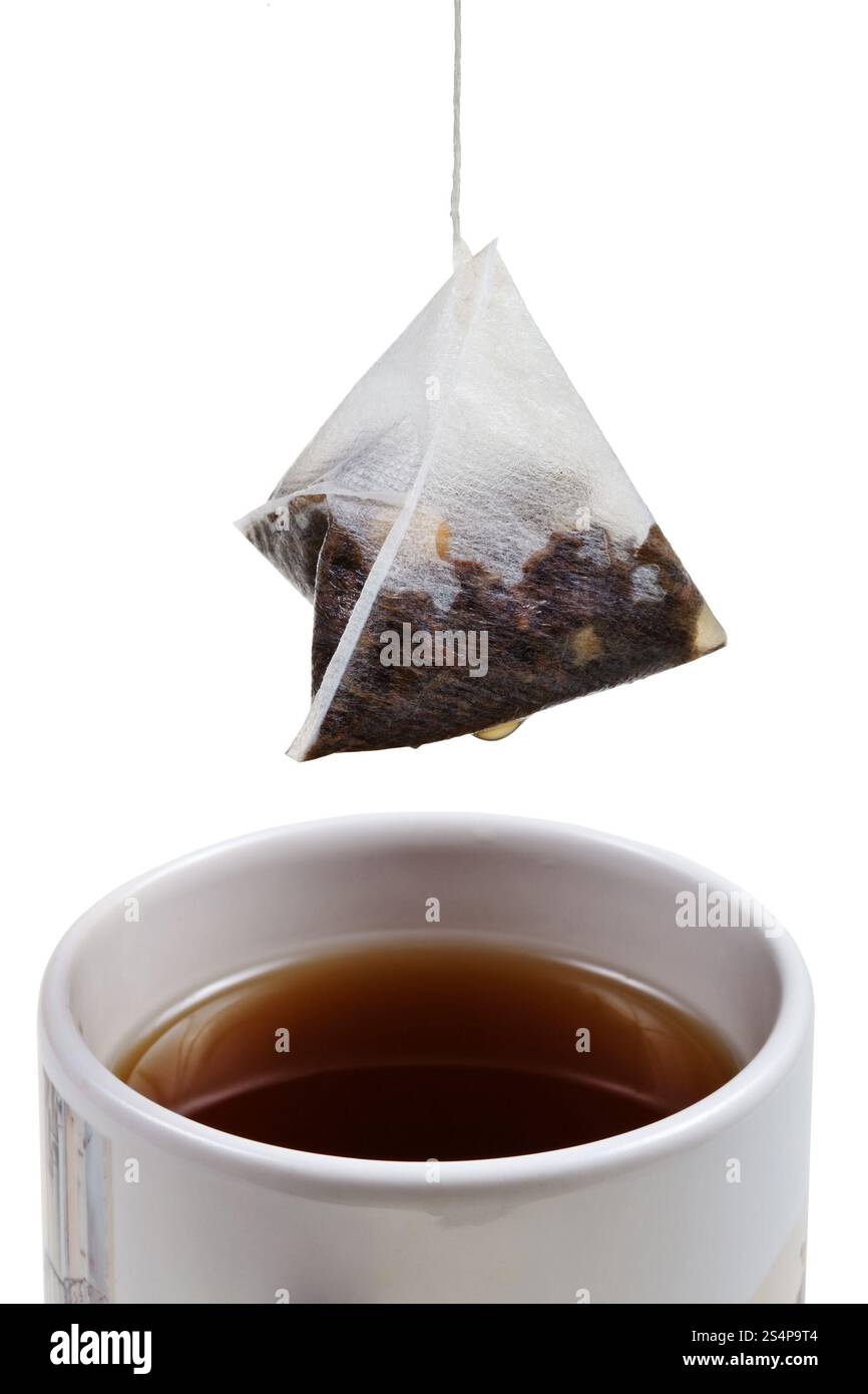tea bag over brewing tea in cup close up isolated on white background ...