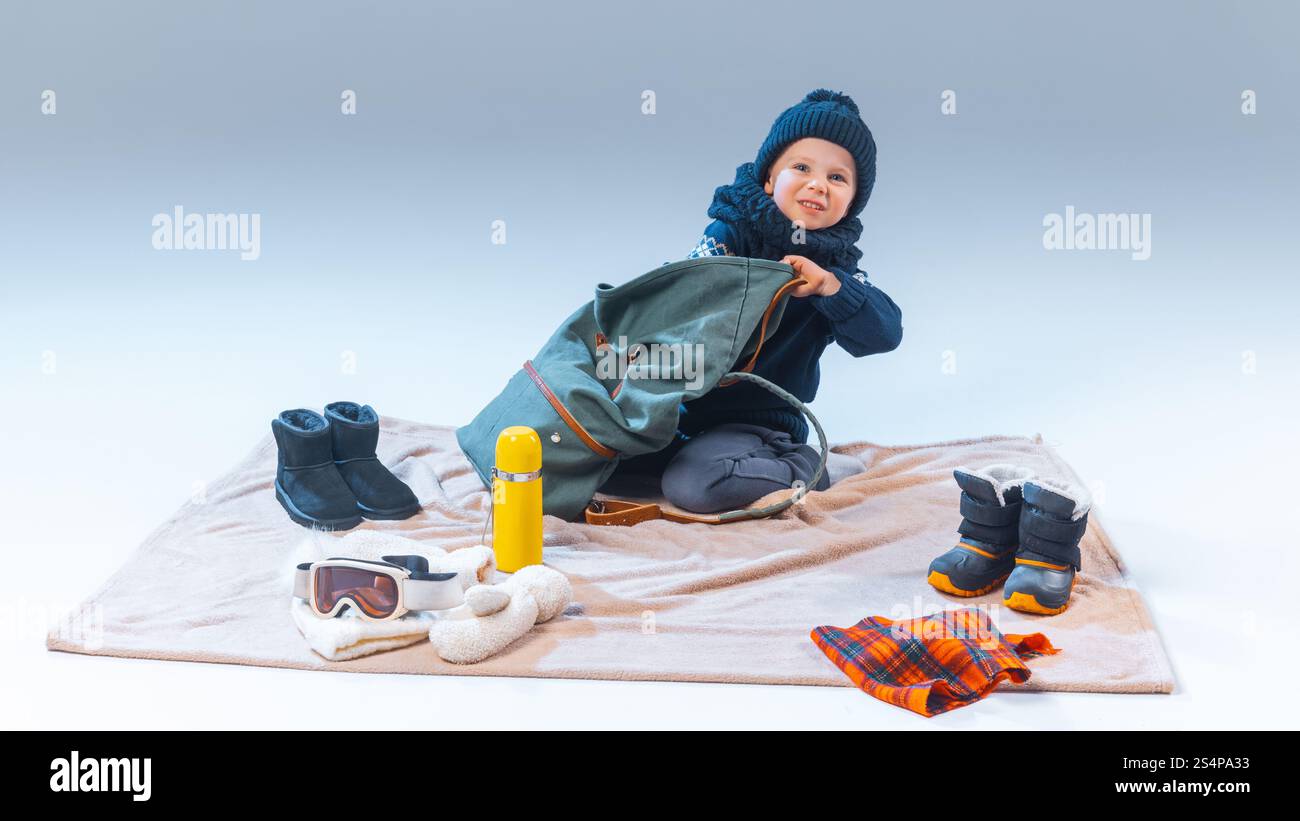 Curious little boy, sitting on floor and trying to find something in ...