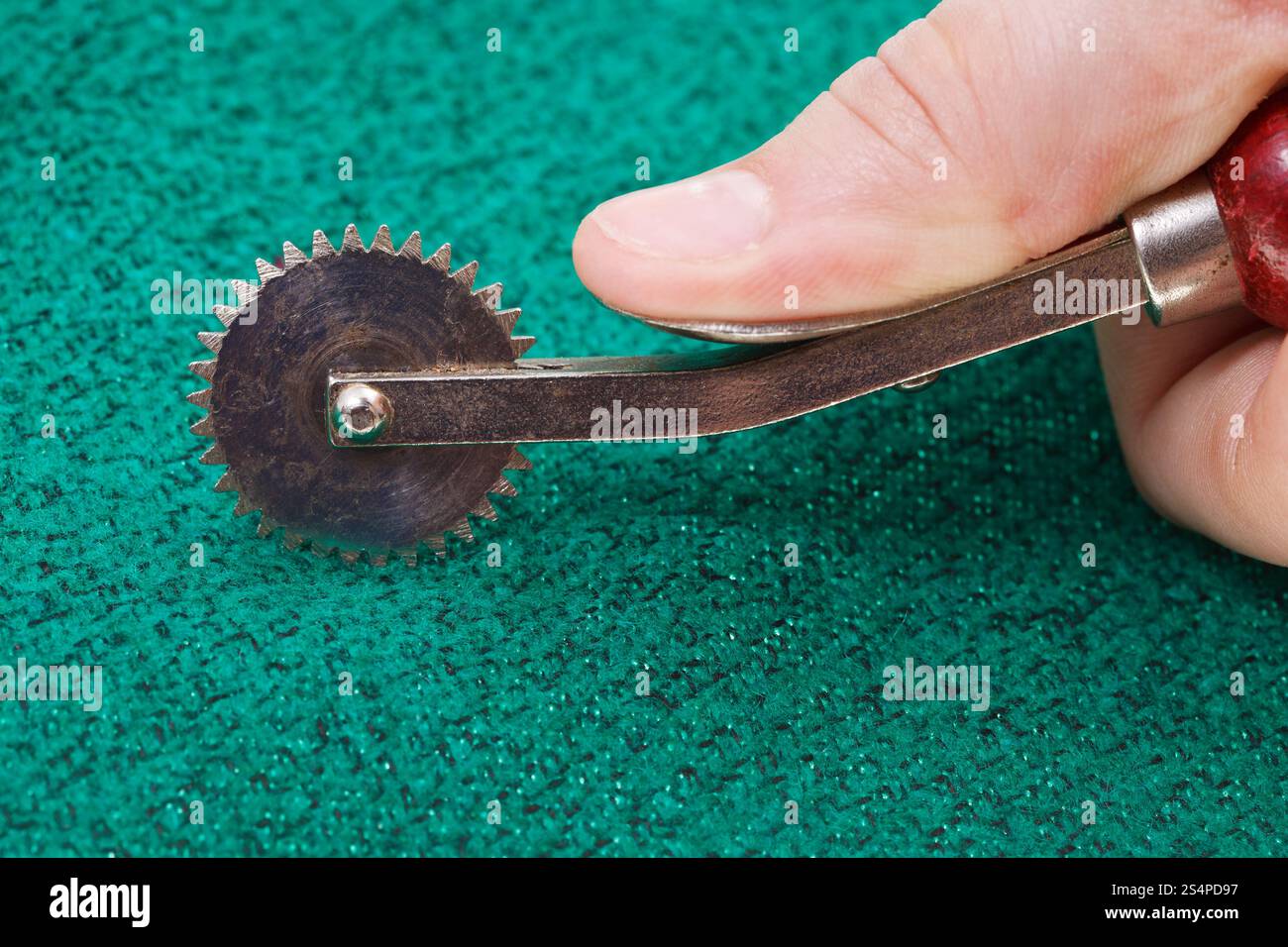 using of sewing tracing wheel on green textile Stock Photo - Alamy