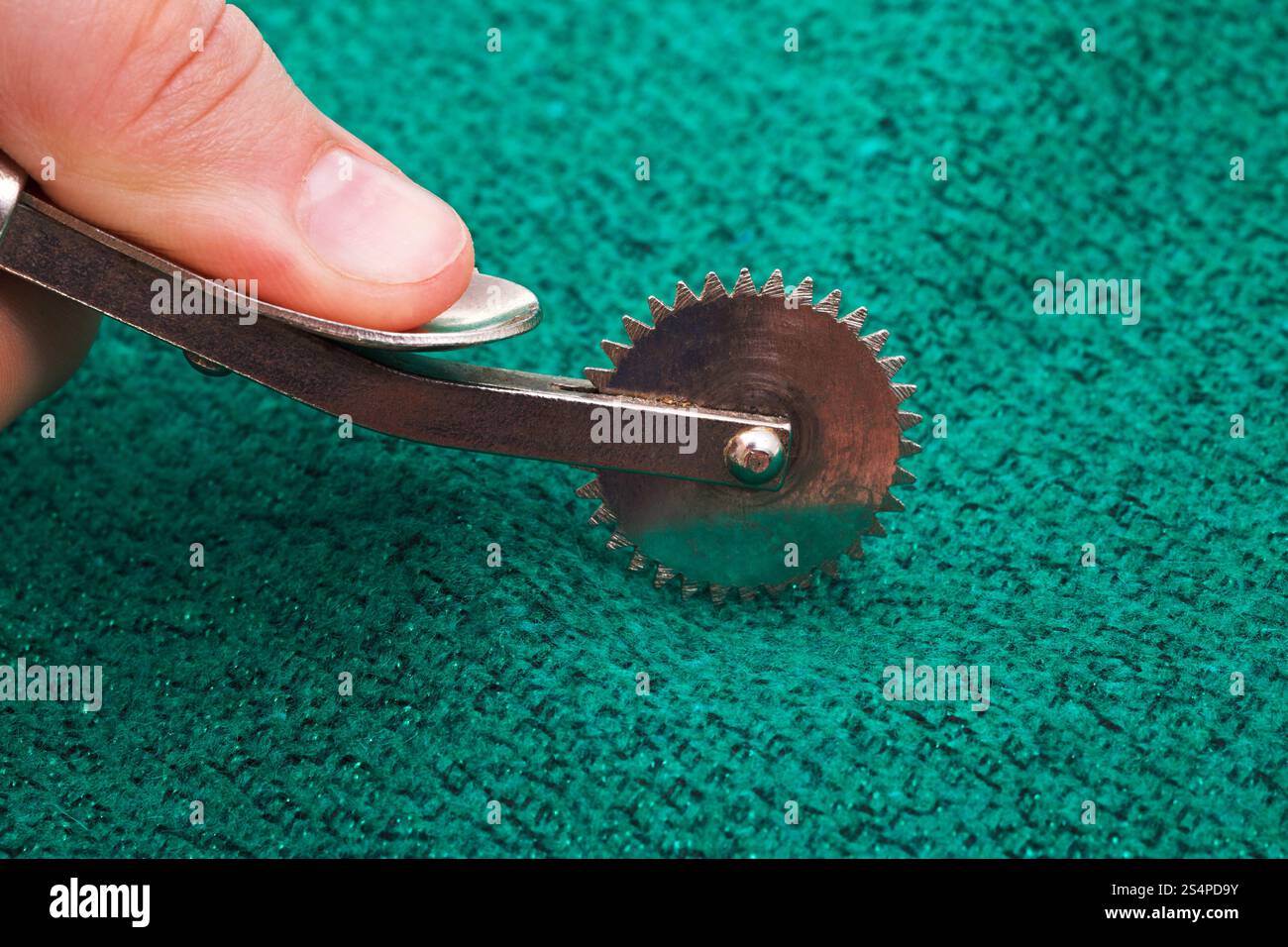 using of sewing tracing wheel on green fabric Stock Photo - Alamy