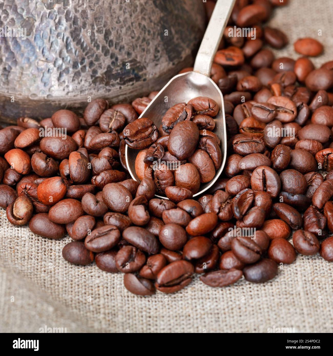 roasted coffee beans and copper coffee pot with spoon close up on ...