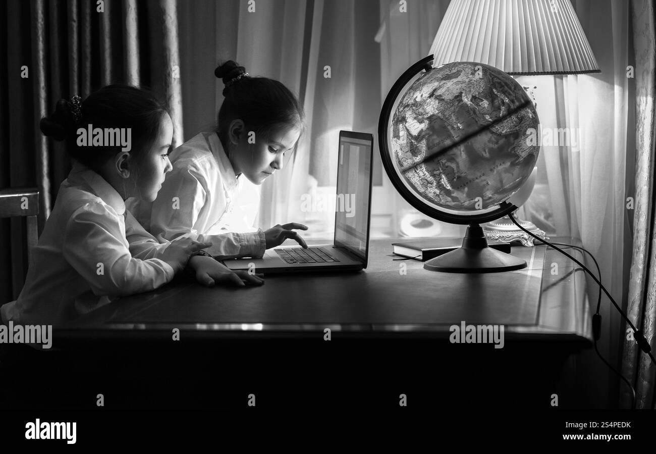 Portrait of two girls typing e-mail on laptop at night Stock Photo - Alamy