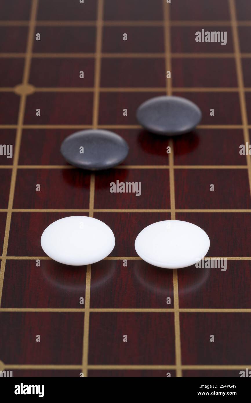 four stones during go game playing on dark wood goban Stock Photo - Alamy