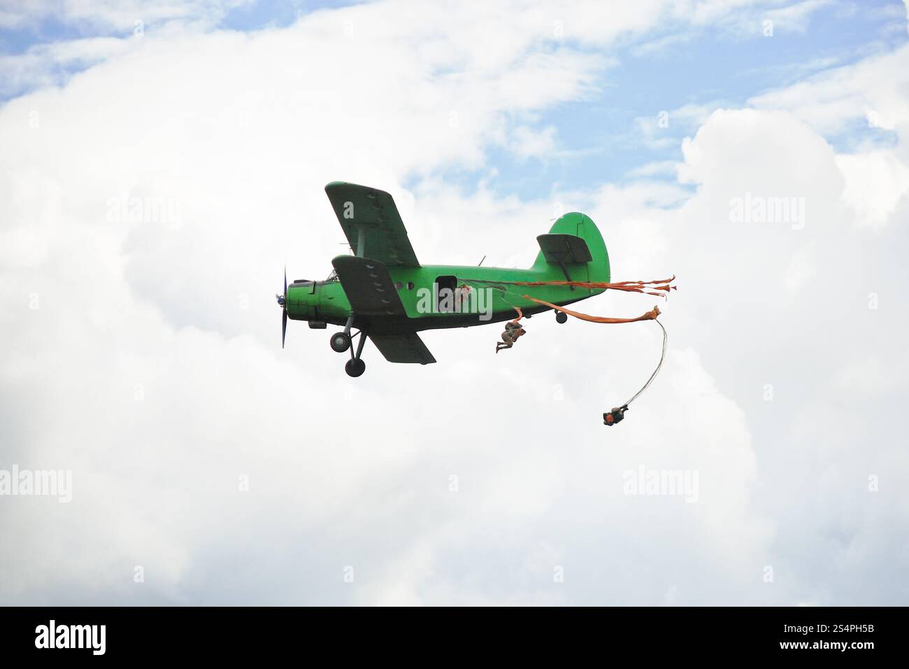 parachuting jump from small green aircraft in white clouds Stock Photo ...