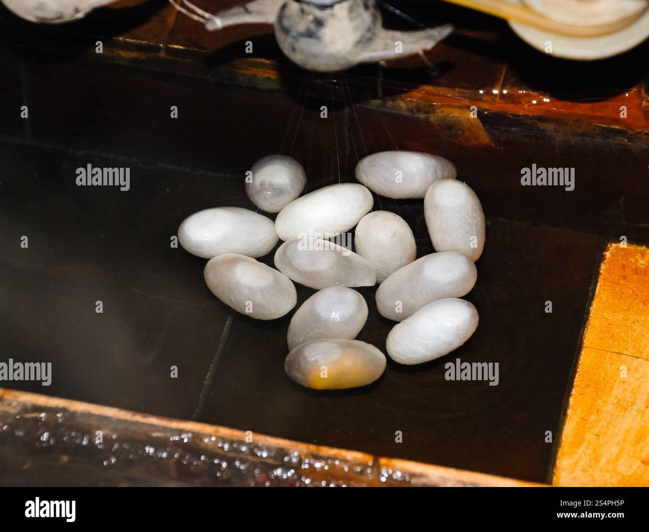 Extracting raw silk fibre from cocoons on traditional Chinese factory ...