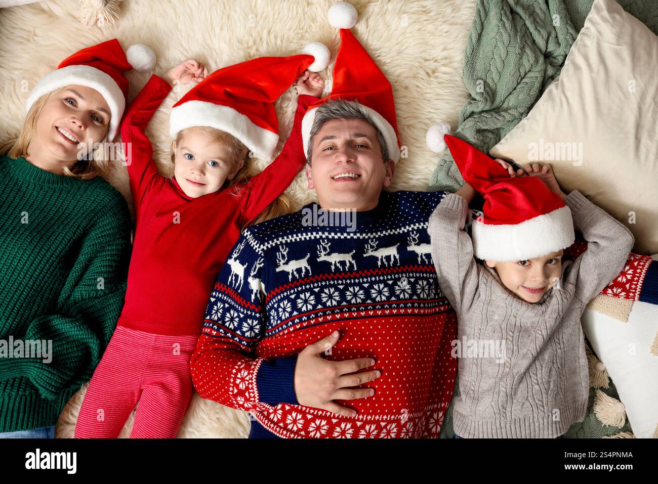 Happy family in Santa hats lying on rug together, top view. Christmas ...