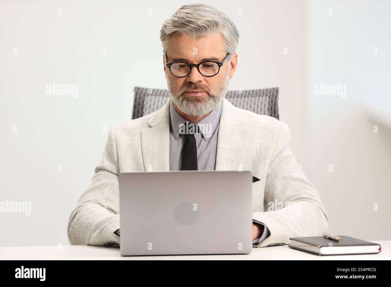 Banker working on laptop at desk in office Stock Photo - Alamy