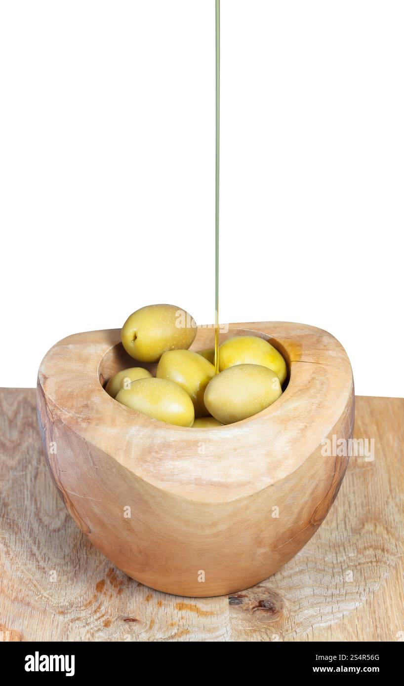 olive oil in thin stream flows on olives in wooden bowl close up ...