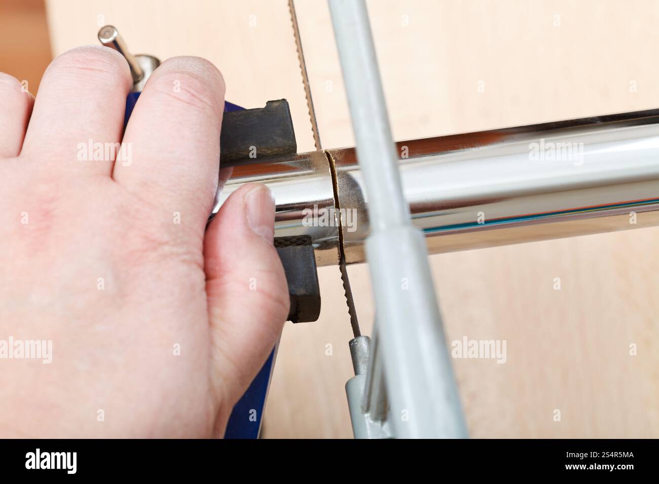 metalworker saws metal plumbing pipe gripped in vice by hacksaw close ...