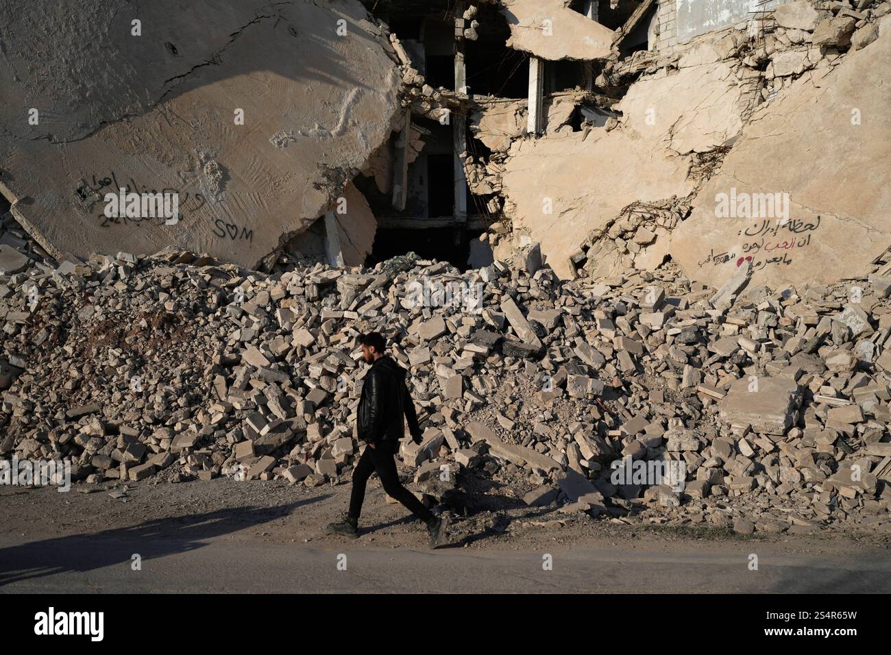 A man walks past the rubble of a war-damaged building in Saraqib, on ...