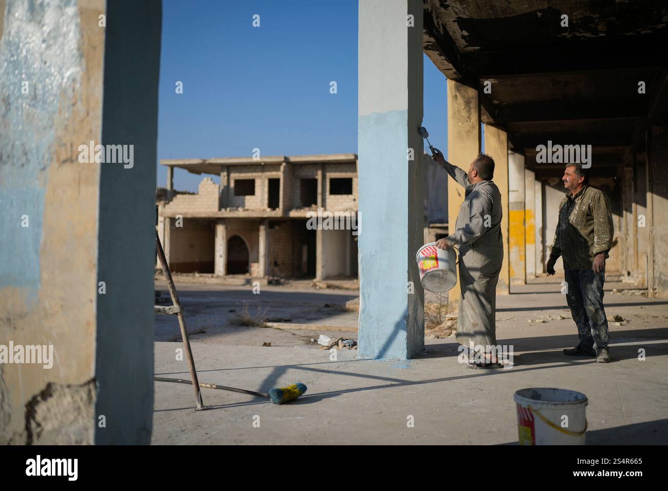 A man paints a column while reconstructing a war-damaged building in ...