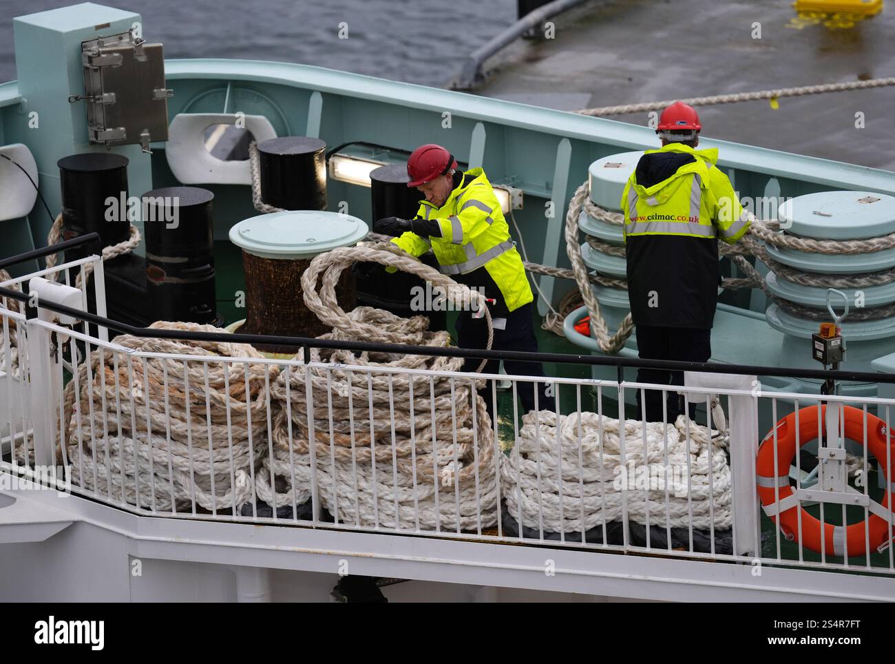 Workers pull ropes on board The Glen Sannox ferry ahead of departing ...