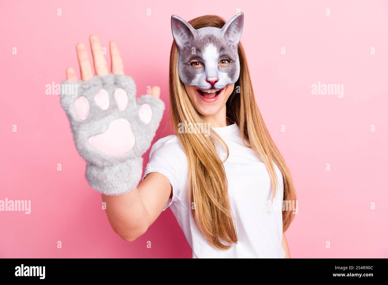 Young woman disguised as a cat with a playful paw gesture on a vibrant ...