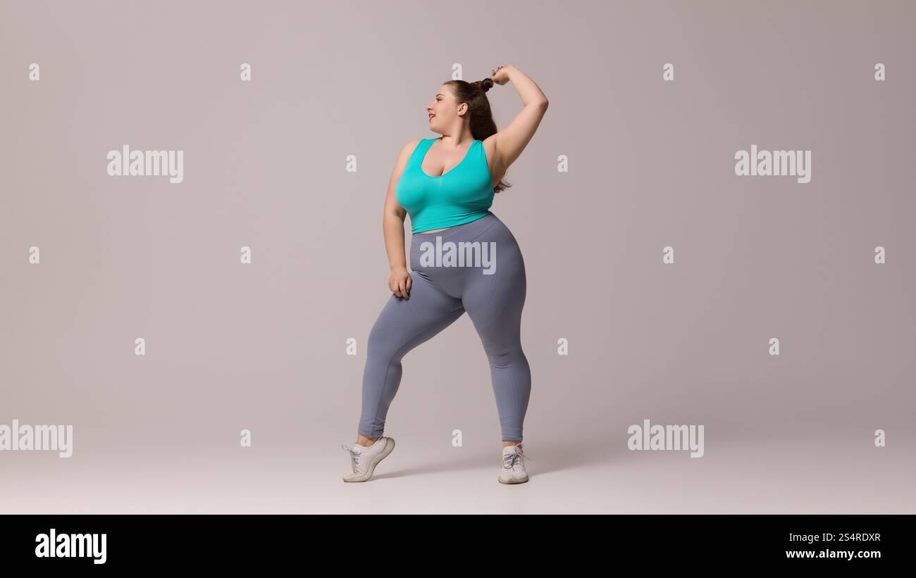 Overweight woman in blue top and leggings with hand behind head ...